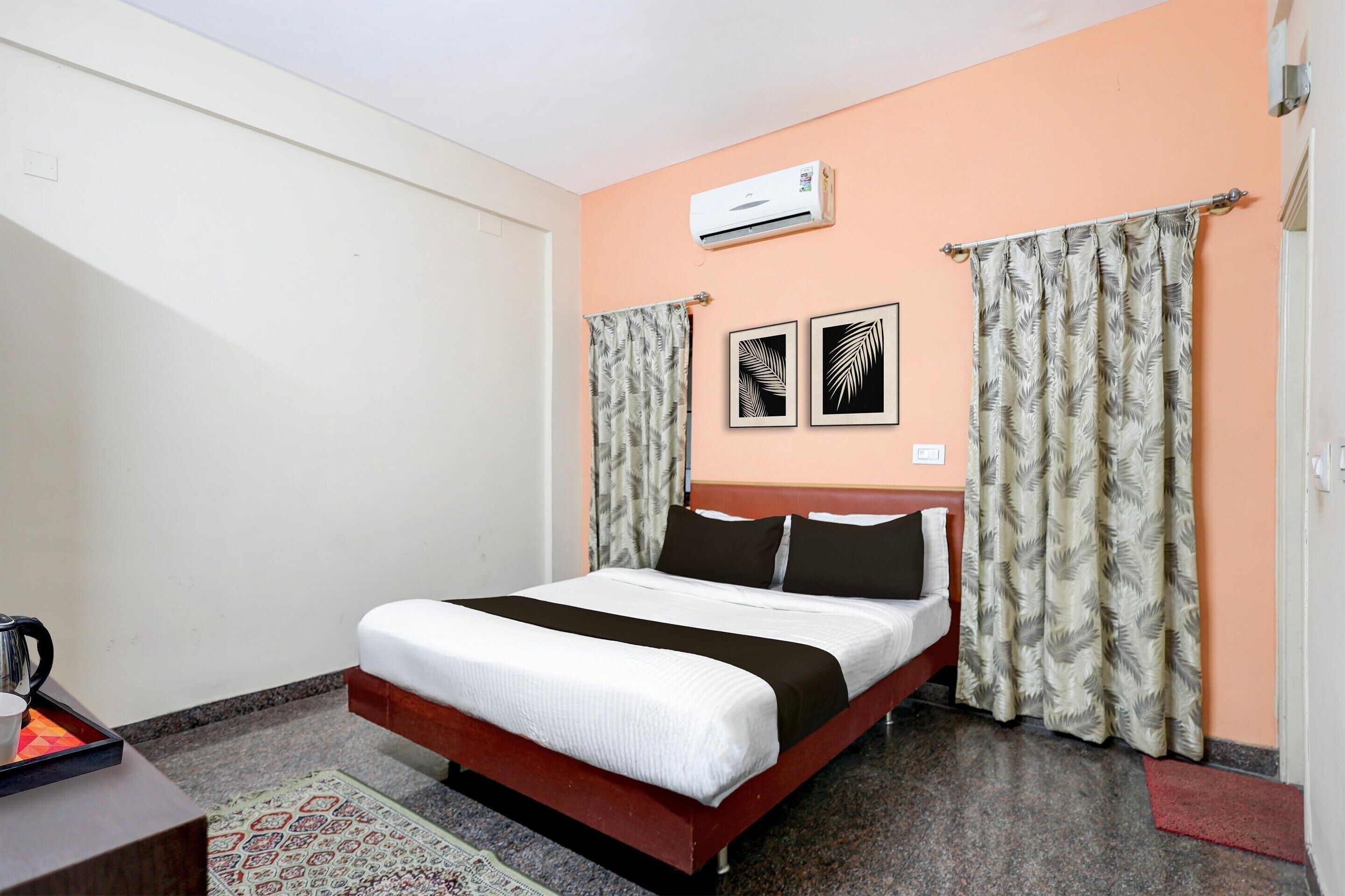 Quarto de hotel com cama, ar condicionado, cortinas e um pequeno tapete.