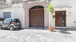 Um edifício com uma grande porta de madeira, um vaso de planta e um carro estacionado.