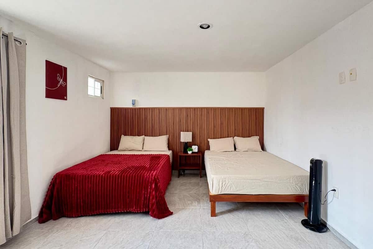 Quarto de hotel com duas camas, uma cabeceira de madeira, mesa de cabeceira com abajur e televisão.
