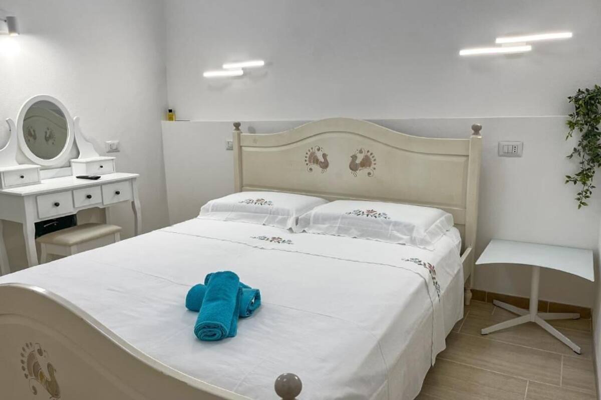 Quarto bem arrumado com cama, mesa de cabeceira e espelho.