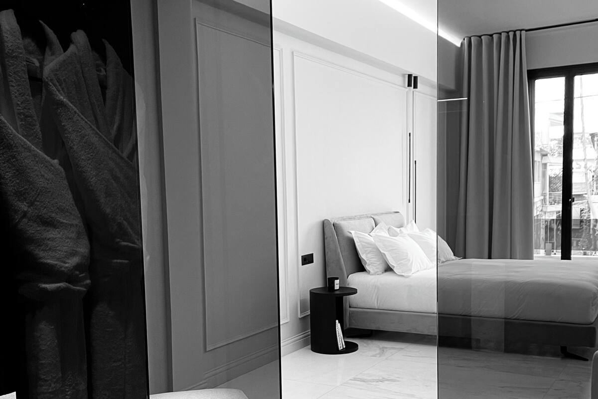 Quarto de hotel moderno com cama, mesa lateral e área de estar.