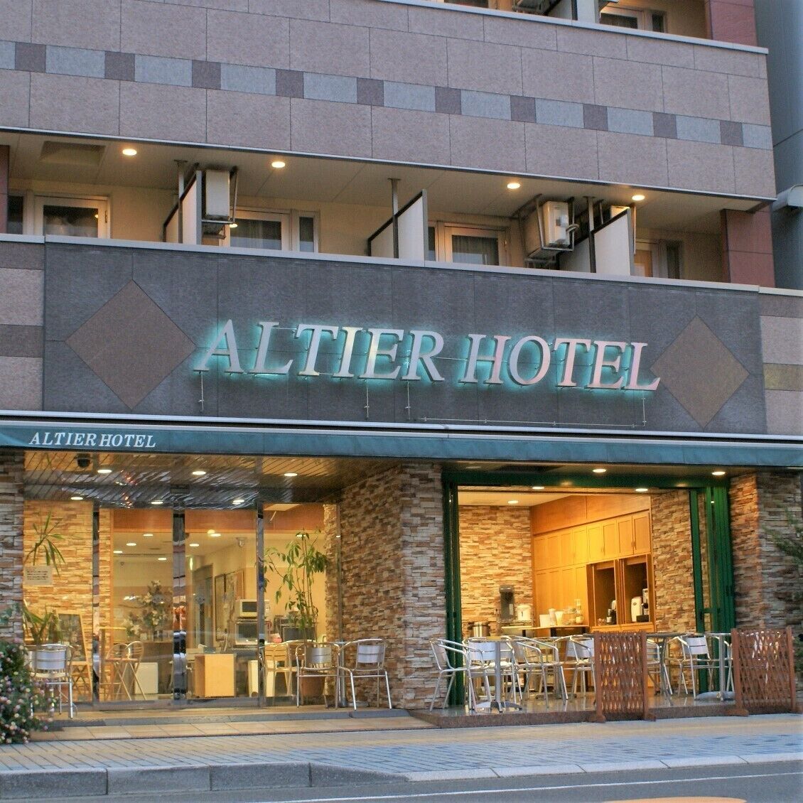 Exterior do Hotel Altier, com fachada moderna, grandes janelas de vidro e área de estar ao ar livre.