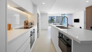 Uma cozinha moderna com armários brancos, eletrodomésticos de aço inoxidável e uma ilha grande com pia.