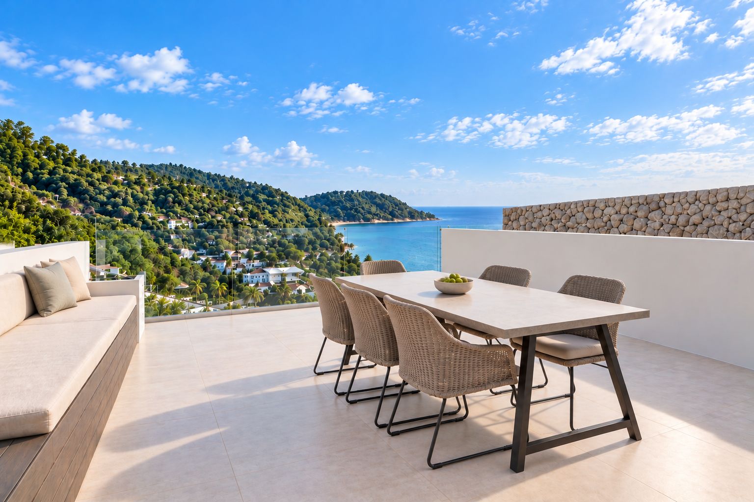 Terraço com mesa e cadeiras, com vista para paisagem costeira com colinas e céu claro.