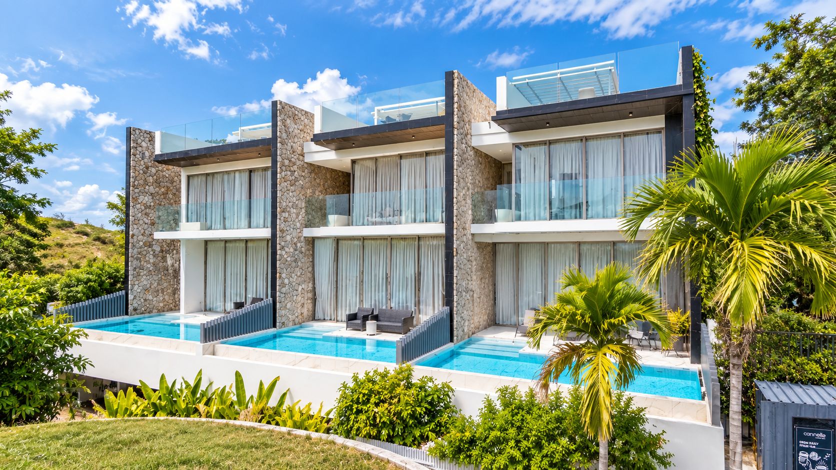 Uma casa moderna de vários andares com piscina, fachada de pedra e vegetação exuberante.