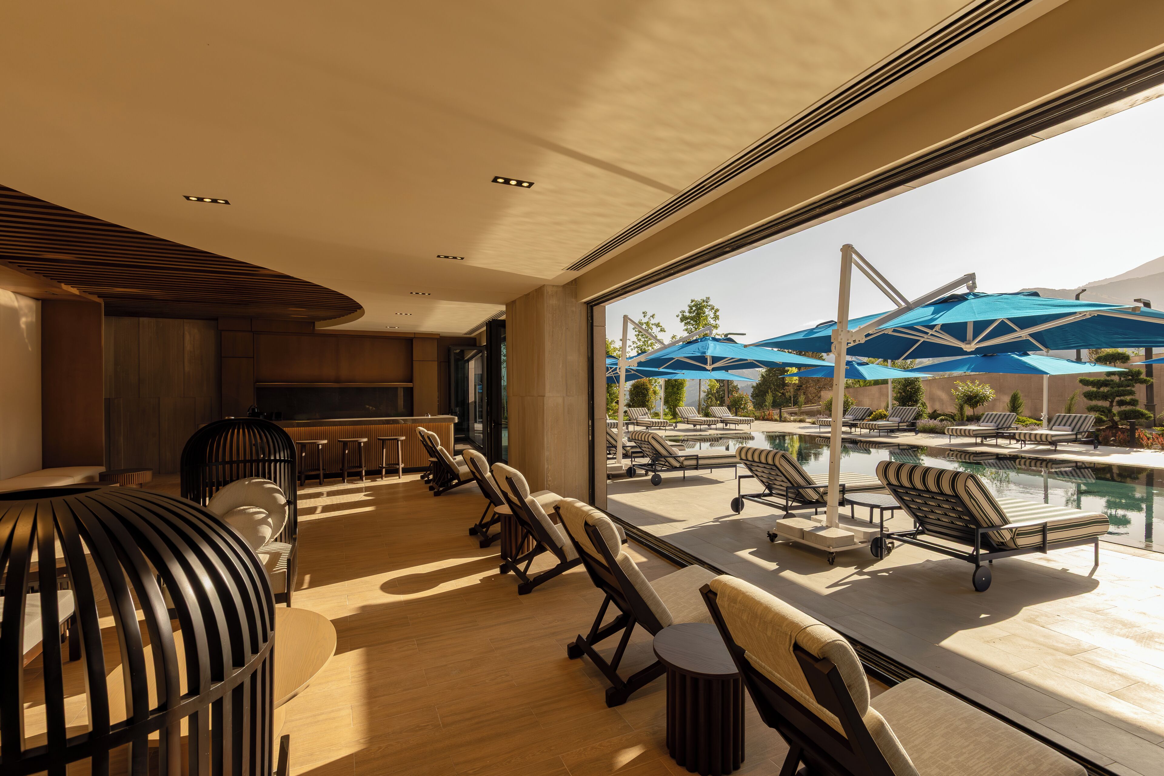 Um hall de hotel moderno com vista para a piscina, cadeiras de lounge e área de bar.