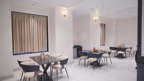 Uma sala de conferências moderna com uma mesa grande, várias cadeiras e uma janela ampla com cortinas.