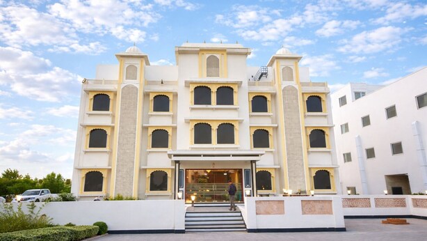 Um hotel de vários andares com entrada central, janelas amplas e fachada simétrica.