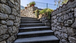 Uma escadaria de pedra que sobe até um muro de pedra com plantas em vasos no topo.