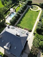 Vista aérea de uma propriedade residencial com piscina, um jardim circular e gramado bem cuidado.