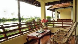 Um deck de madeira com mesa e cadeiras, com vista para um corpo d'água com palmeiras.