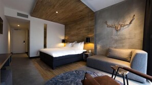 Quarto de hotel moderno com uma cama grande, um sofá e uma obra de arte original na parede.