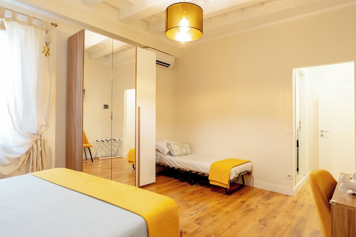 Quarto com cama, uma cadeira, um guarda-roupa e um espelho.