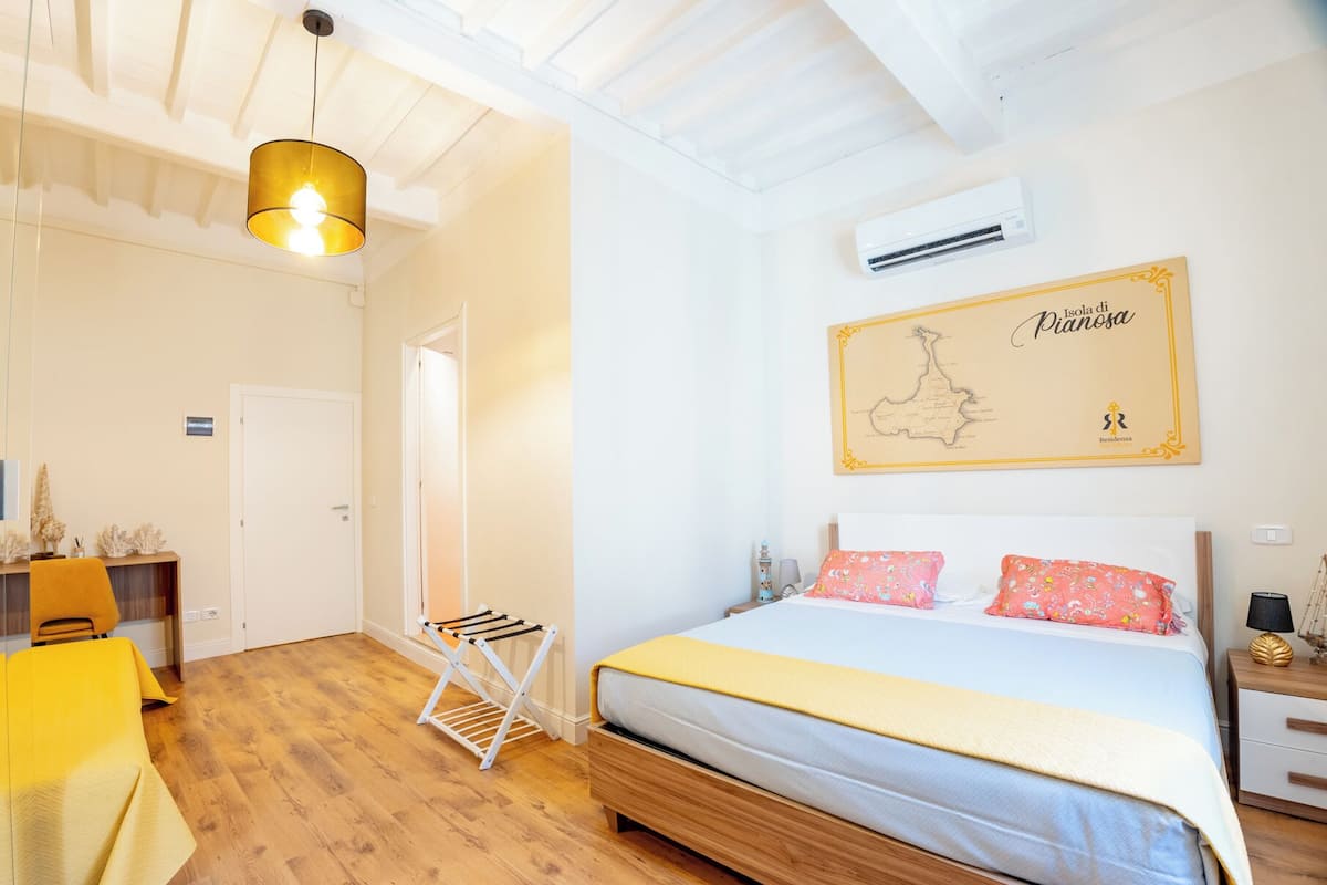 Quarto com cama, um mapa na parede, um varal e piso de madeira.