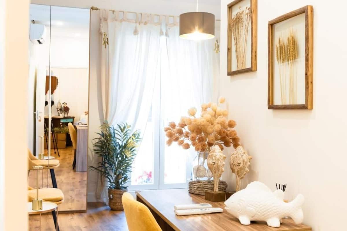 Um interior moderno com uma mesa de jantar de madeira, cadeiras amarelas, uma planta em vaso e quadros nas paredes.