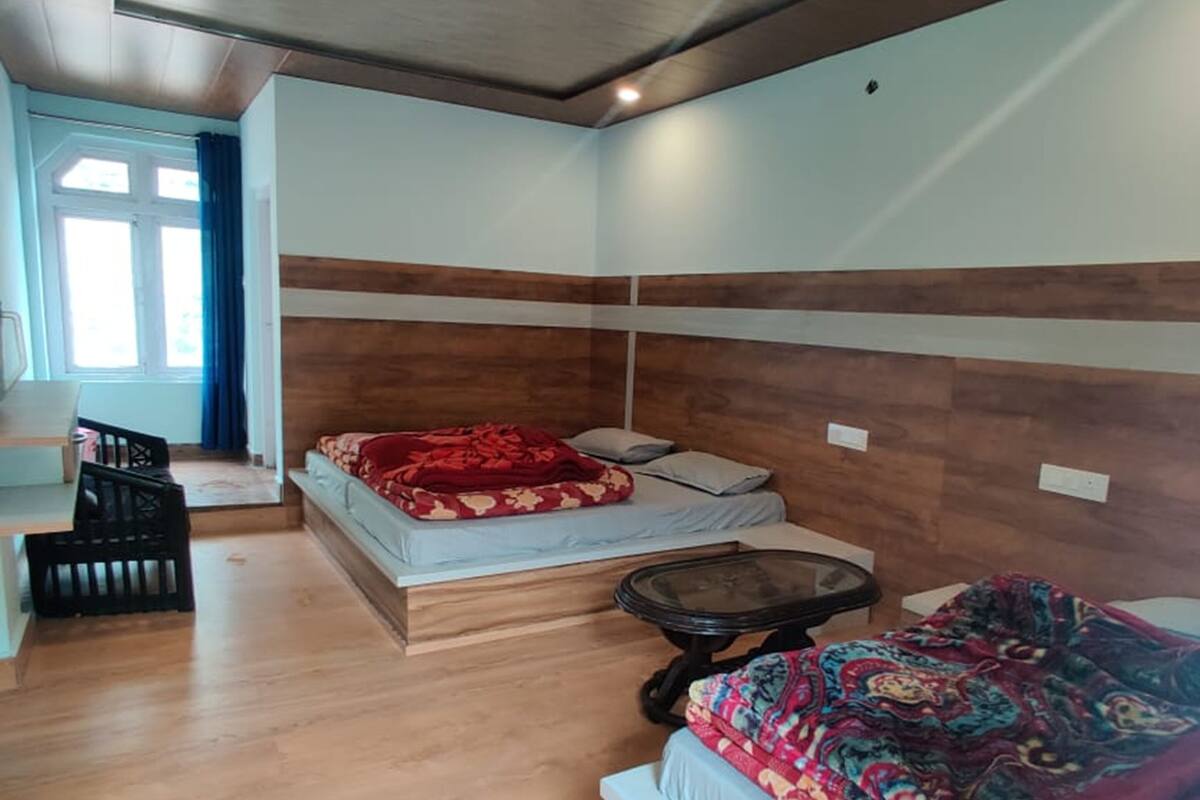 Quarto com duas camas, uma mesa pequena e uma janela.