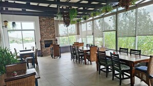 Uma sala de jantar espaçosa com pé direito alto, grandes janelas e plantas pendentes.