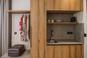 Uma cozinha compacta equipada com pia, cafeteira e prateleira com pratos e copos.