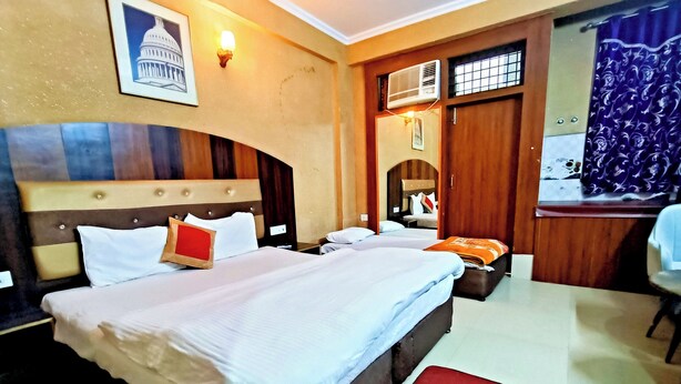 Quarto de hotel com duas camas, um tapete vermelho e um quadro com a imagem de um edifício.