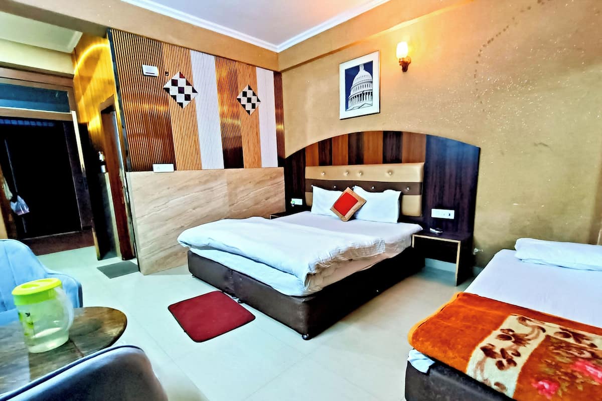 Quarto de hotel com uma cama grande, uma cama menor, uma mesa e uma cadeira.