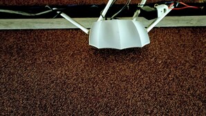 Um aparelho branco com antenas sobre um tapete castanho.