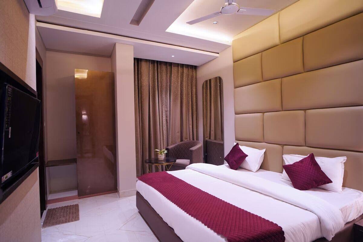 Quarto de hotel moderno com uma cama grande, televisão, área de estar e chuveiro.
