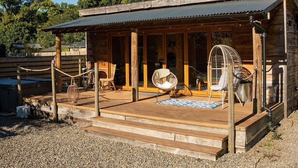 Uma cabana de madeira com varanda coberta, área de estar externa e ventilador.