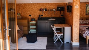 Quarto compacto com cozinha compacta, uma cama e um pequeno espaço de estar.