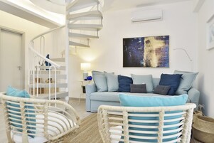 Uma sala de estar moderna com uma escada em espiral, um sofá azul claro e cadeiras de vime.