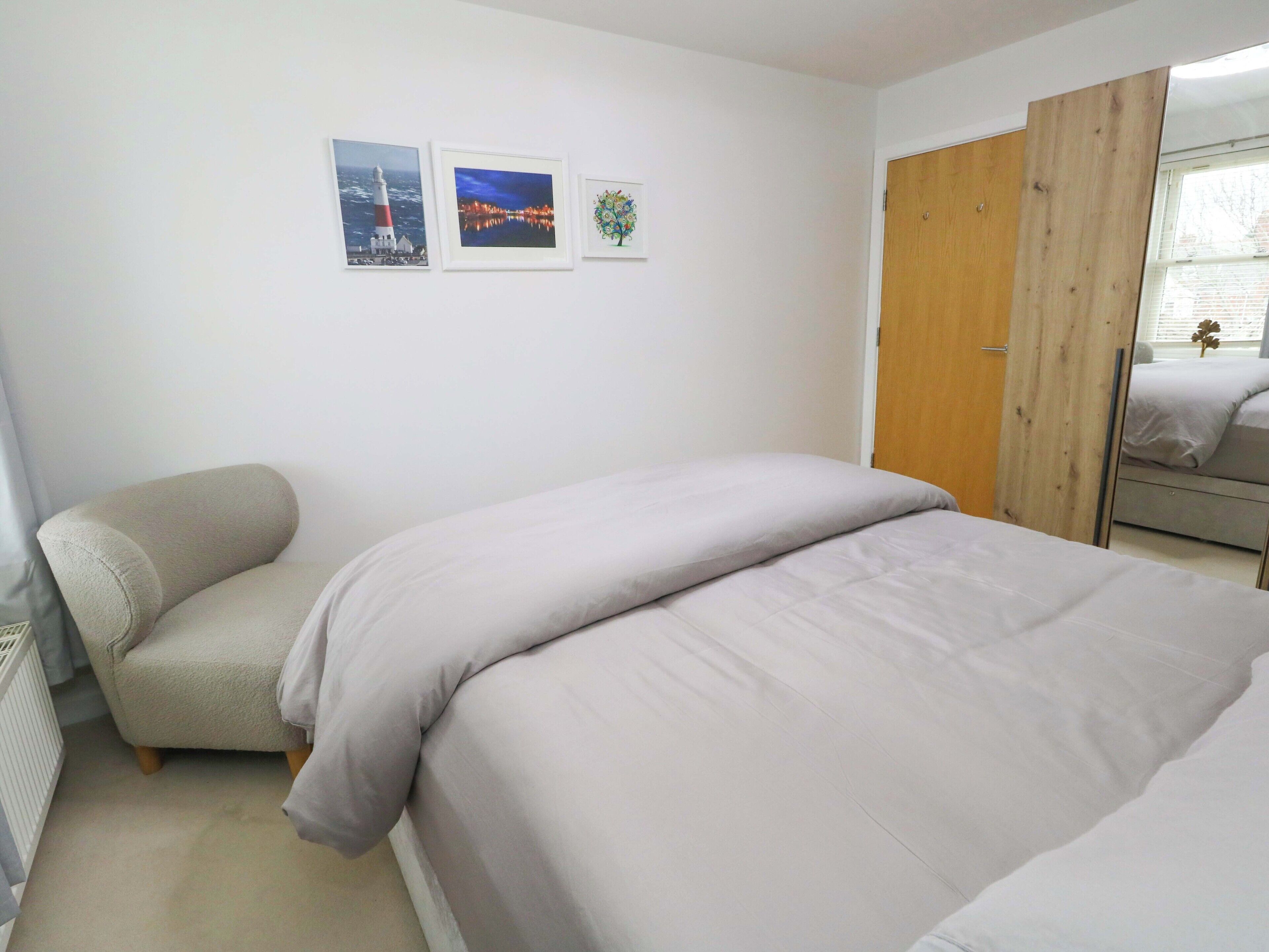 Um quarto com uma cama, uma cadeira e um guarda-roupa.