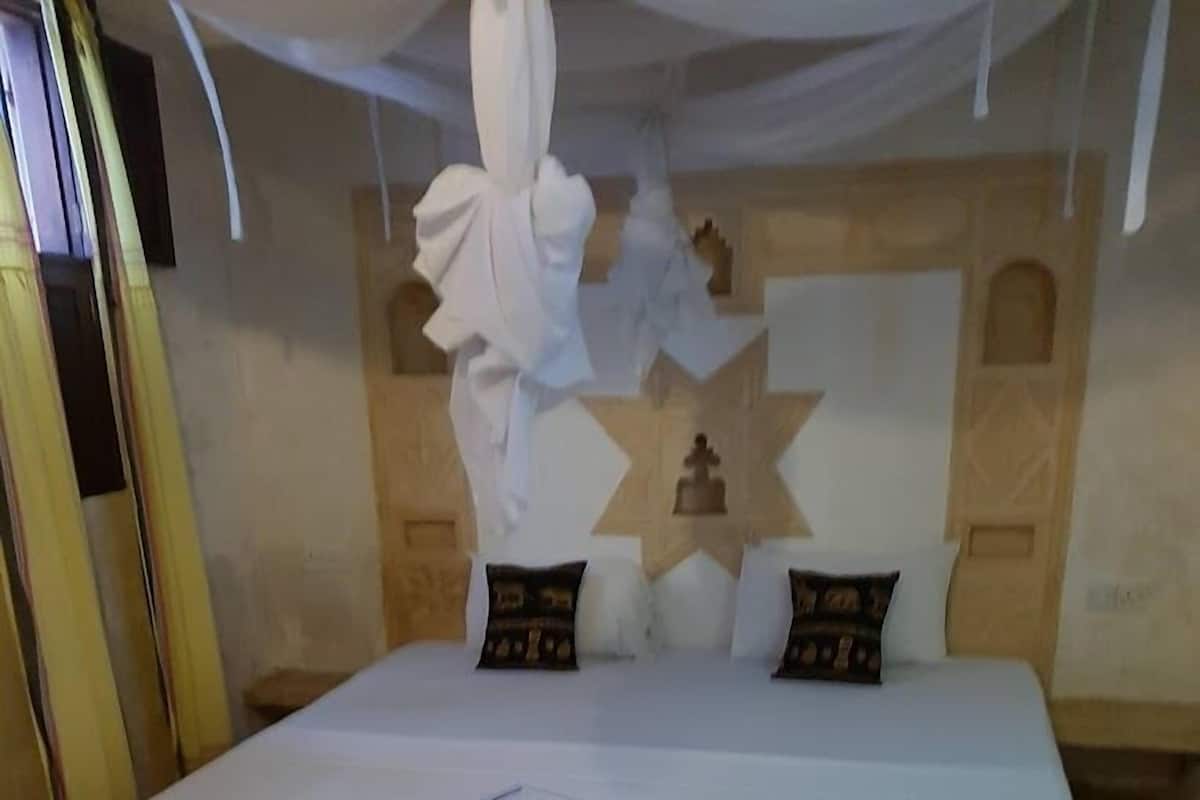 Uma cama com cabeceira, almofadas e dossel.