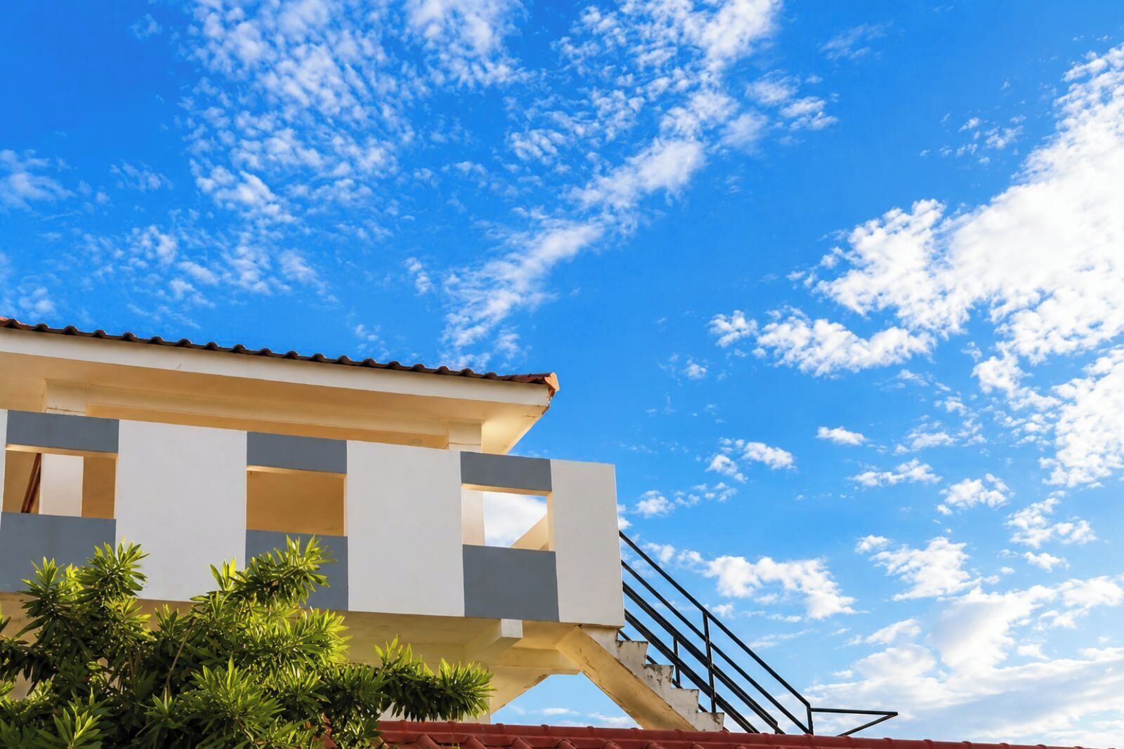 Um edifício moderno com telhado plano, janelas amplas e uma escadaria que leva a um andar superior.