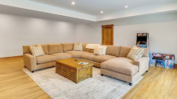Uma sala de estar com um sofá seccional, uma mesa de centro de madeira e um tapete.