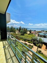 Uma varanda com vista para um jardim cuidado, um corpo d'água e montanhas ao longe.