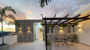 Um terraço no telhado com pérgola, plantas em vasos e um muro de pedra.
