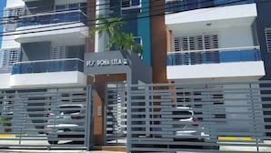Um edifício com vários andares, entrada com portão, varandas e uma placa indicando 