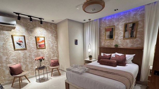 Quarto moderno com uma cama grande, toucador e área de estar.