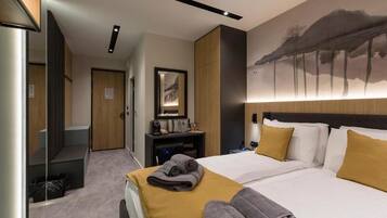 Quarto de hotel moderno com uma cama grande, uma escrivaninha e um espelho.