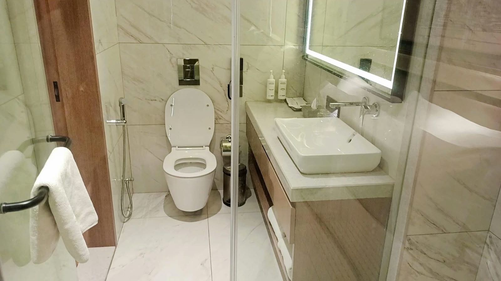Casa de banho moderna com sanita, lavatório e cabine de duche em vidro.