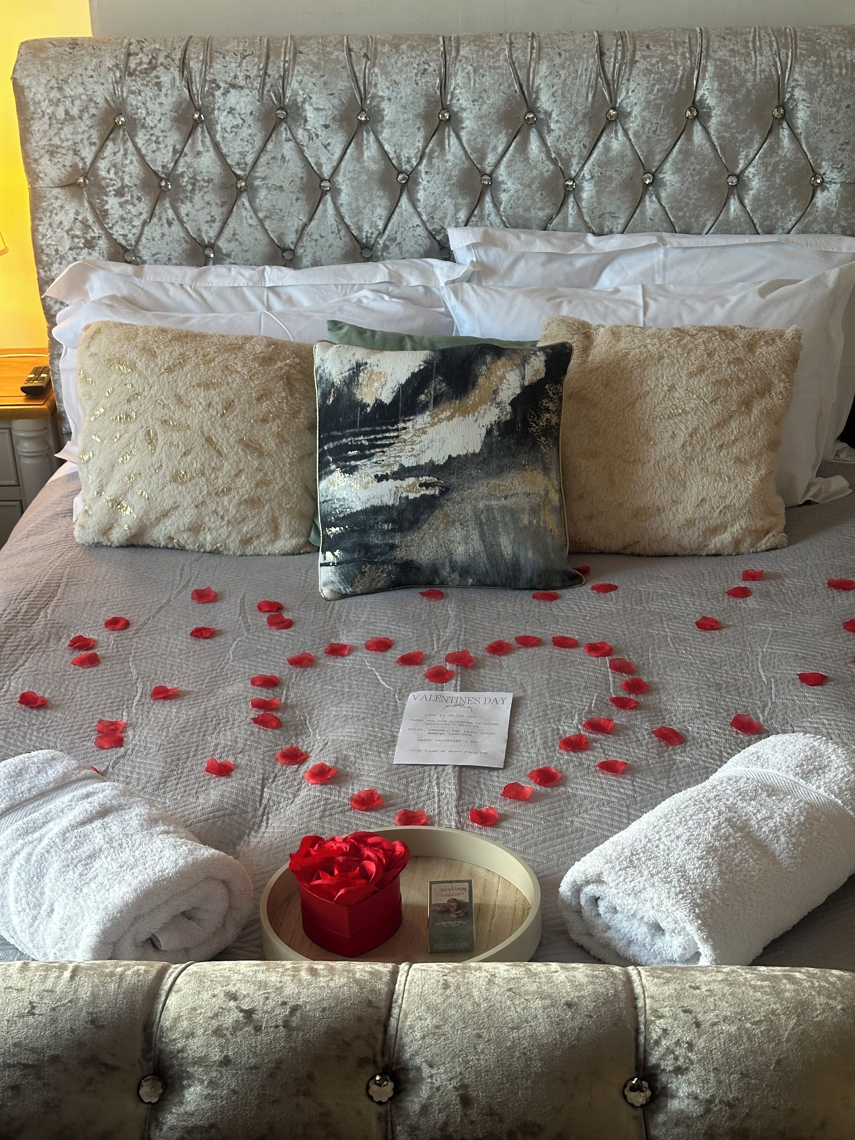 Uma cama bem arrumada com cabeceira estofada, roupa de cama branca e um travesseiro decorativo.