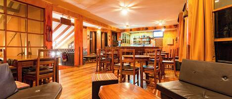 Um restaurante acolhedor com mobiliário de madeira, um bar e uma lareira.