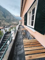 Varanda com bancos de madeira e vista para uma paisagem montanhosa.