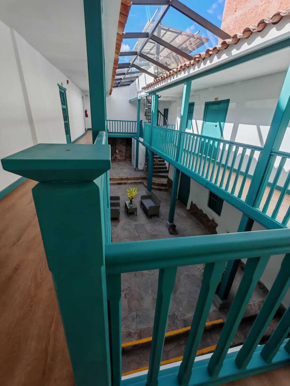 Área externa coberta com piso de madeira, uma escada e um espaço de estar com mesa e cadeiras.