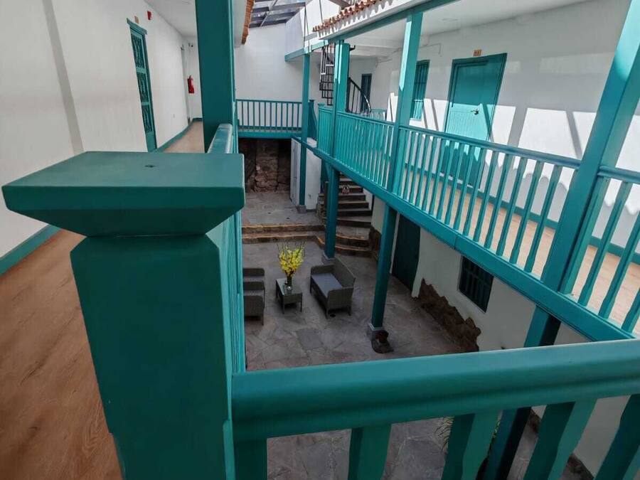 Área externa coberta com piso de madeira, uma escada e um espaço de estar com mesa e cadeiras.
