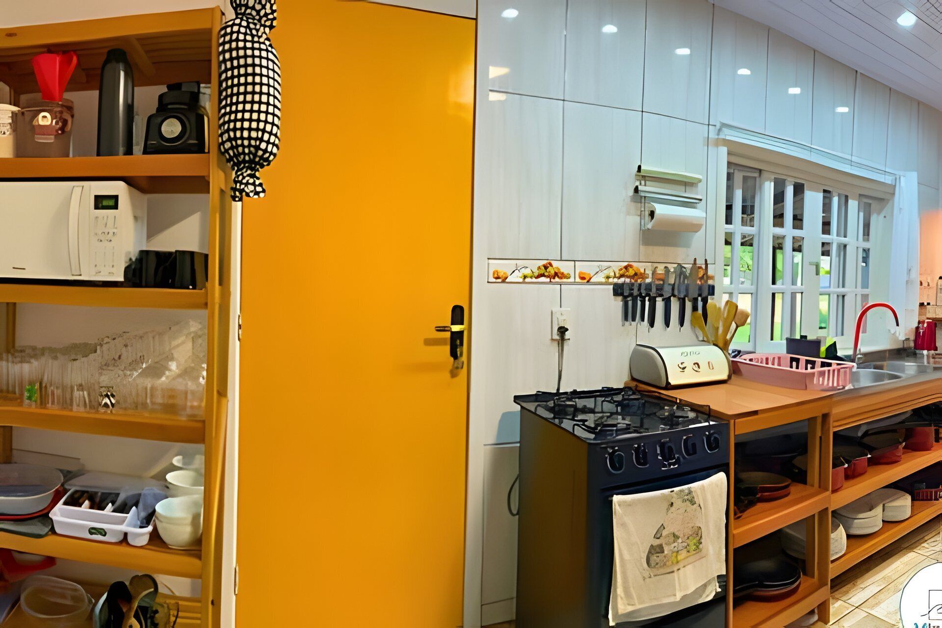 Uma cozinha com uma porta amarela, um fogão e diversos utensílios de cozinha.