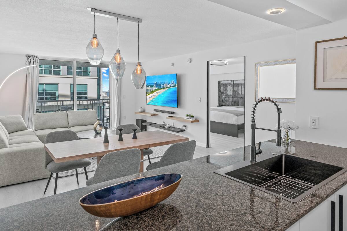 Uma sala de estar moderna com sofá, mesa de jantar e área de cozinha.