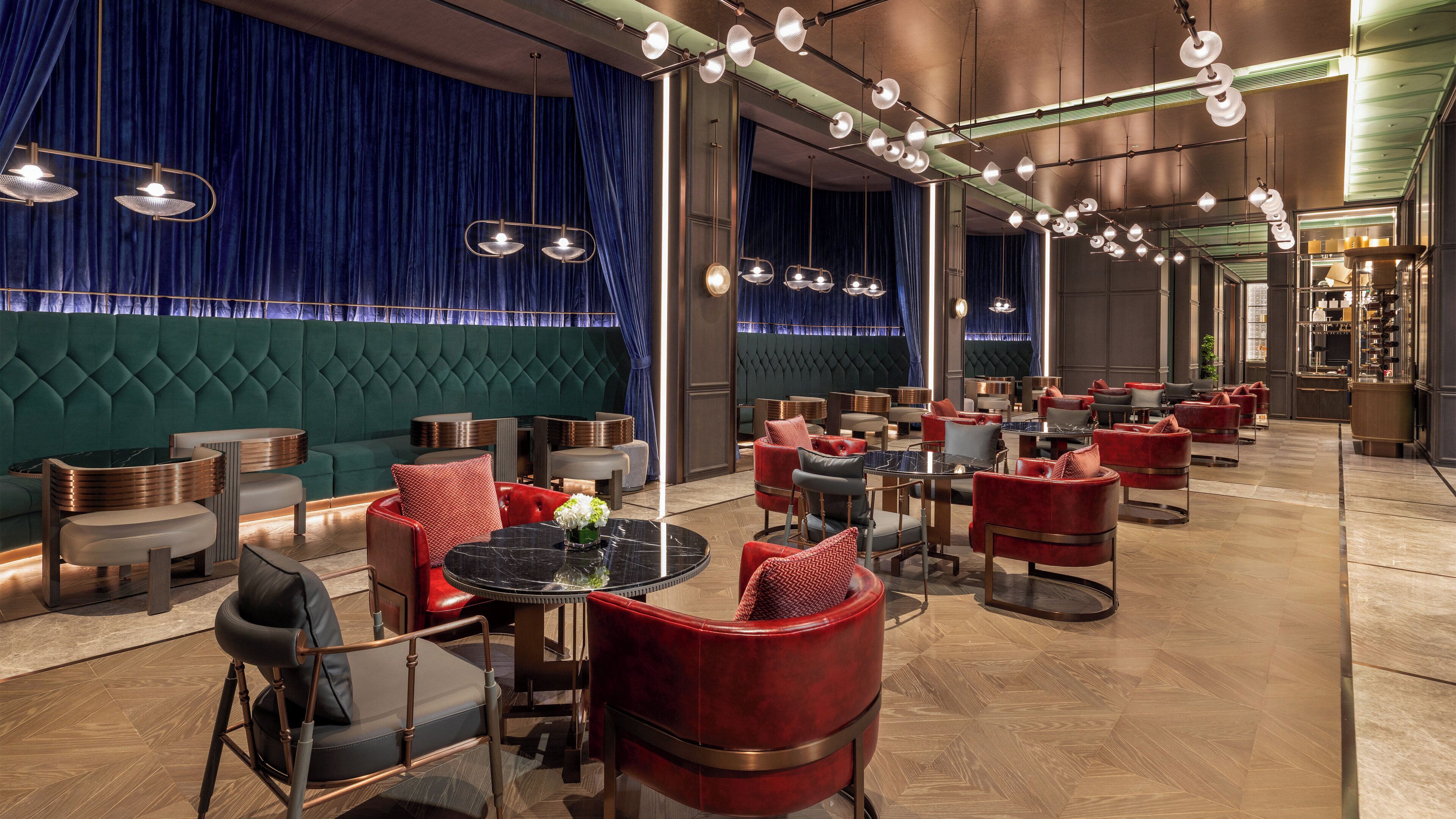 Um restaurante moderno com cortinas de veludo, assentos em níveis e iluminação pendente.