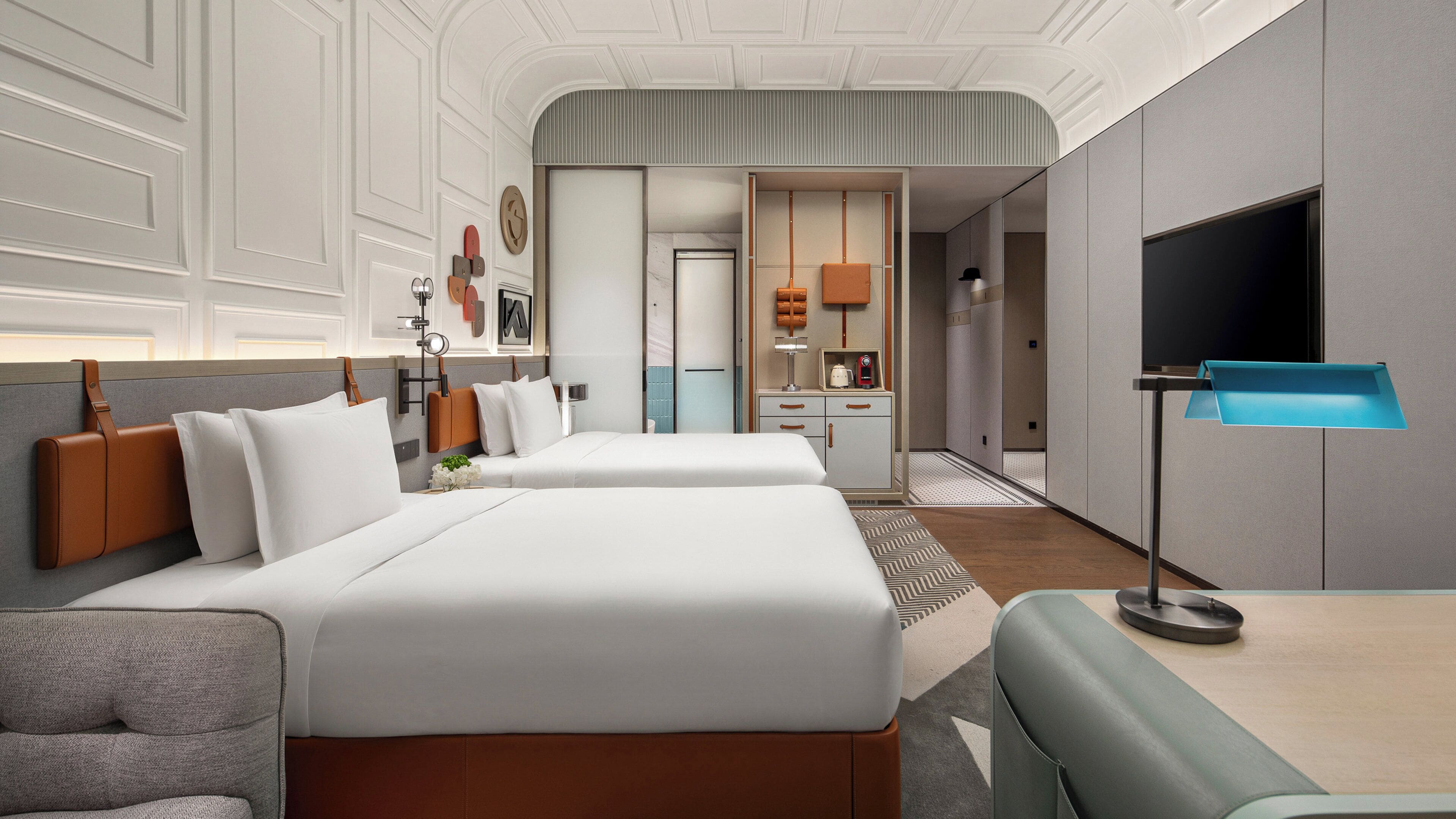Quarto de hotel com cama grande, mesas de cabeceira, escrivaninha, televisão e banheiro visível por uma porta aberta.