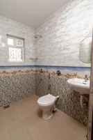 Casa de banho com design em parede de mármore, sanita, lavatório e janela.