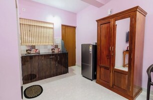 Uma cozinha compacta com geladeira, armários de madeira e uma janela com persianas.